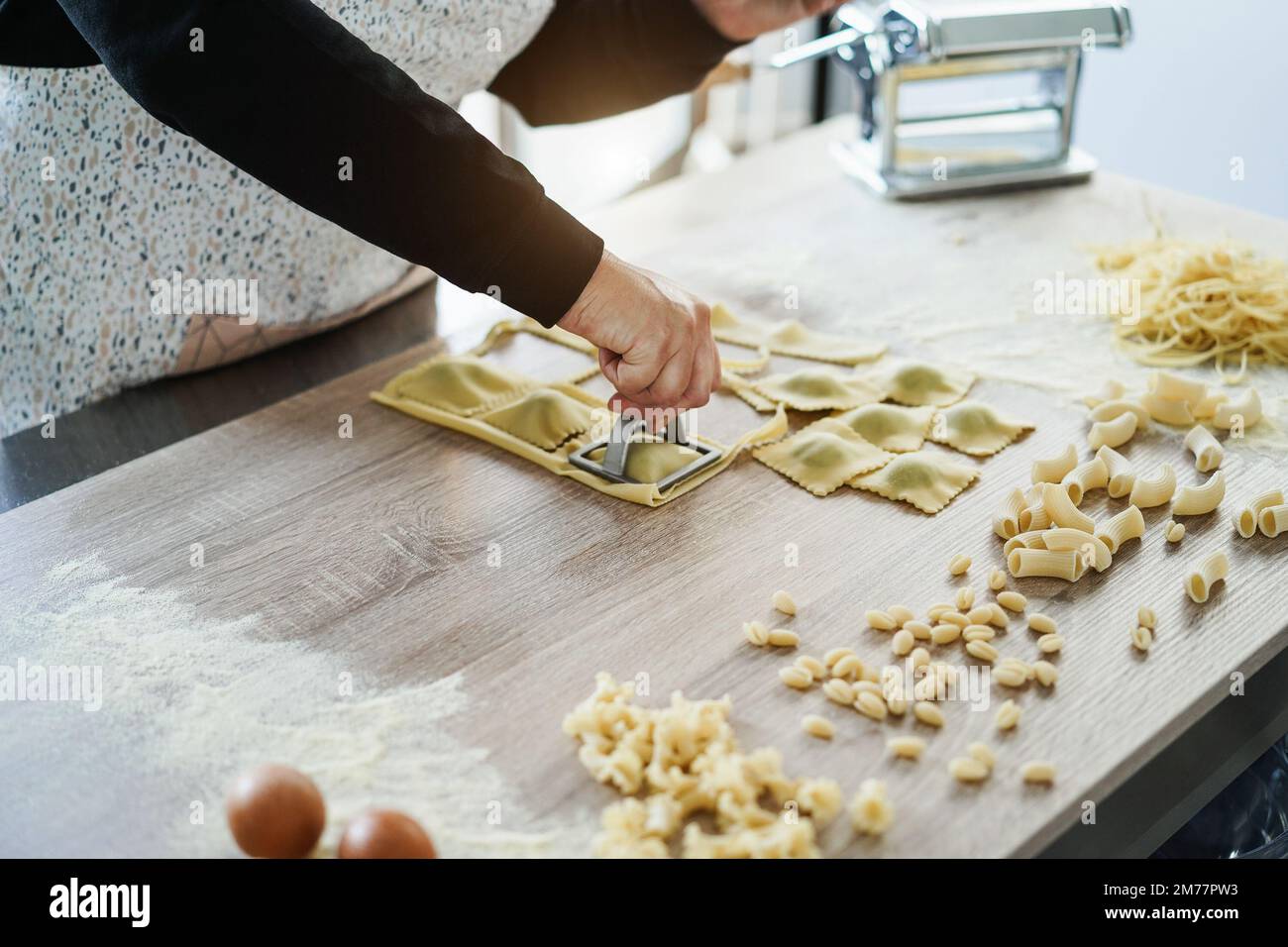 Woman prepare fresh ravioli inside pasta factory - Focus on center hand ...