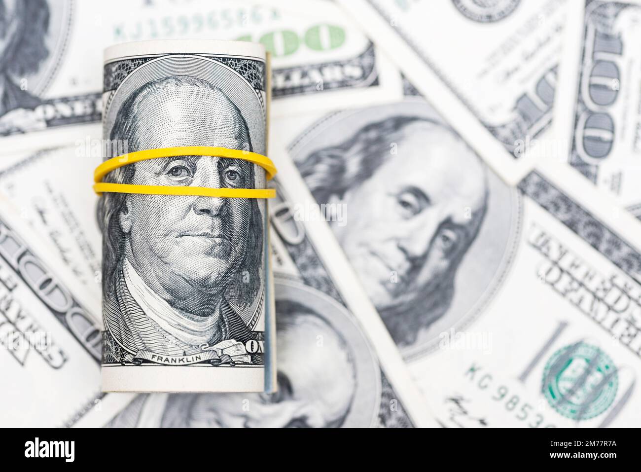 A roll of 100 dollar bills closeup on pile of American dollars ...