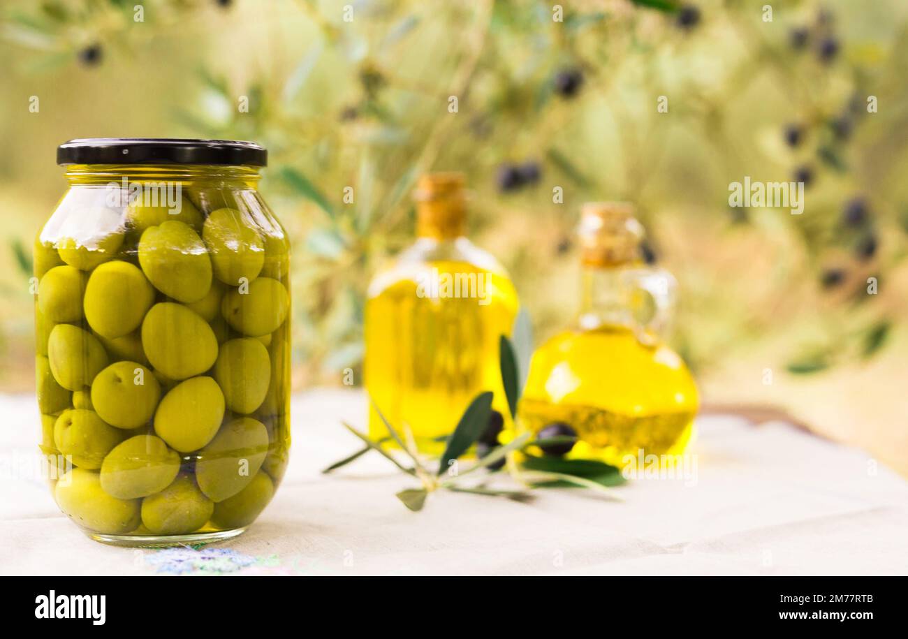 canned olives in a glass jar, oil and olives on the table against the ...
