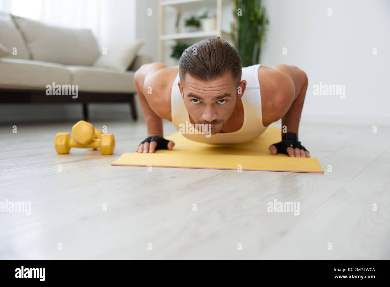 Man sports home training on the floor on a mat with dumbbells ...