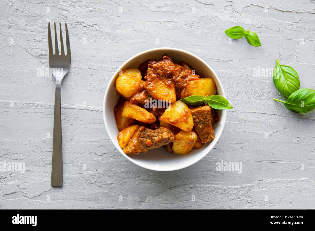 Beef stew with potatoes on grey background, top view Stock Photo - Alamy