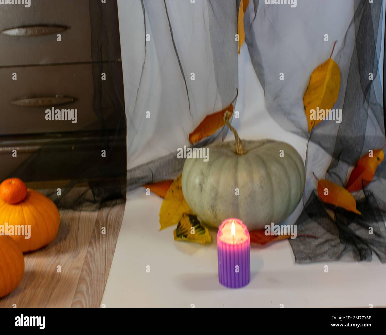 still life with pumpkins and a candle on a background of colorful ...
