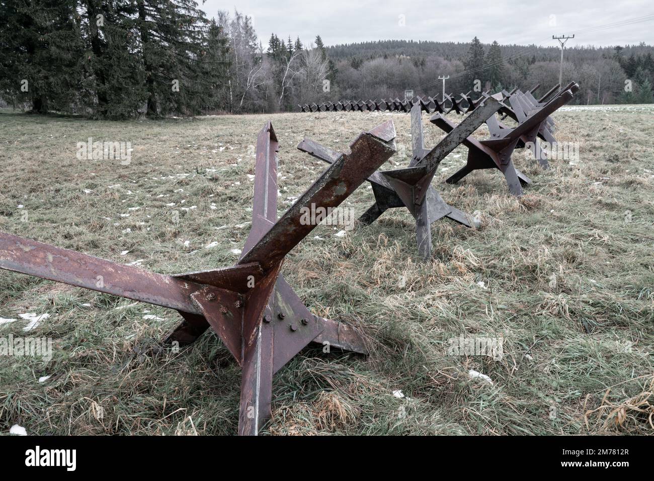 Old steel rusty anti tank roadblocks laid on grass with forest in the ...