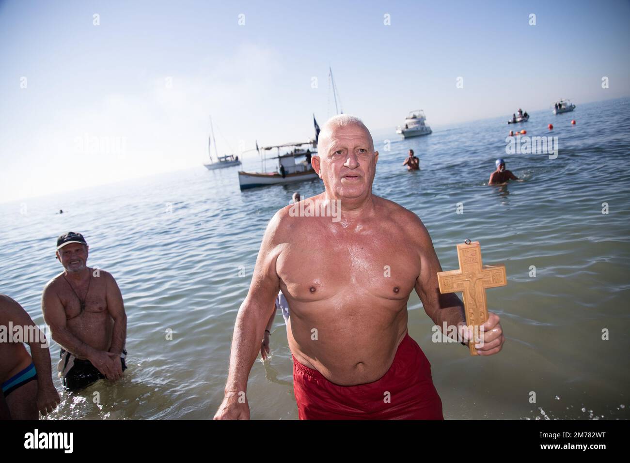 A Greek Orthodox believer holds a wooden cross thrown into the sea ...