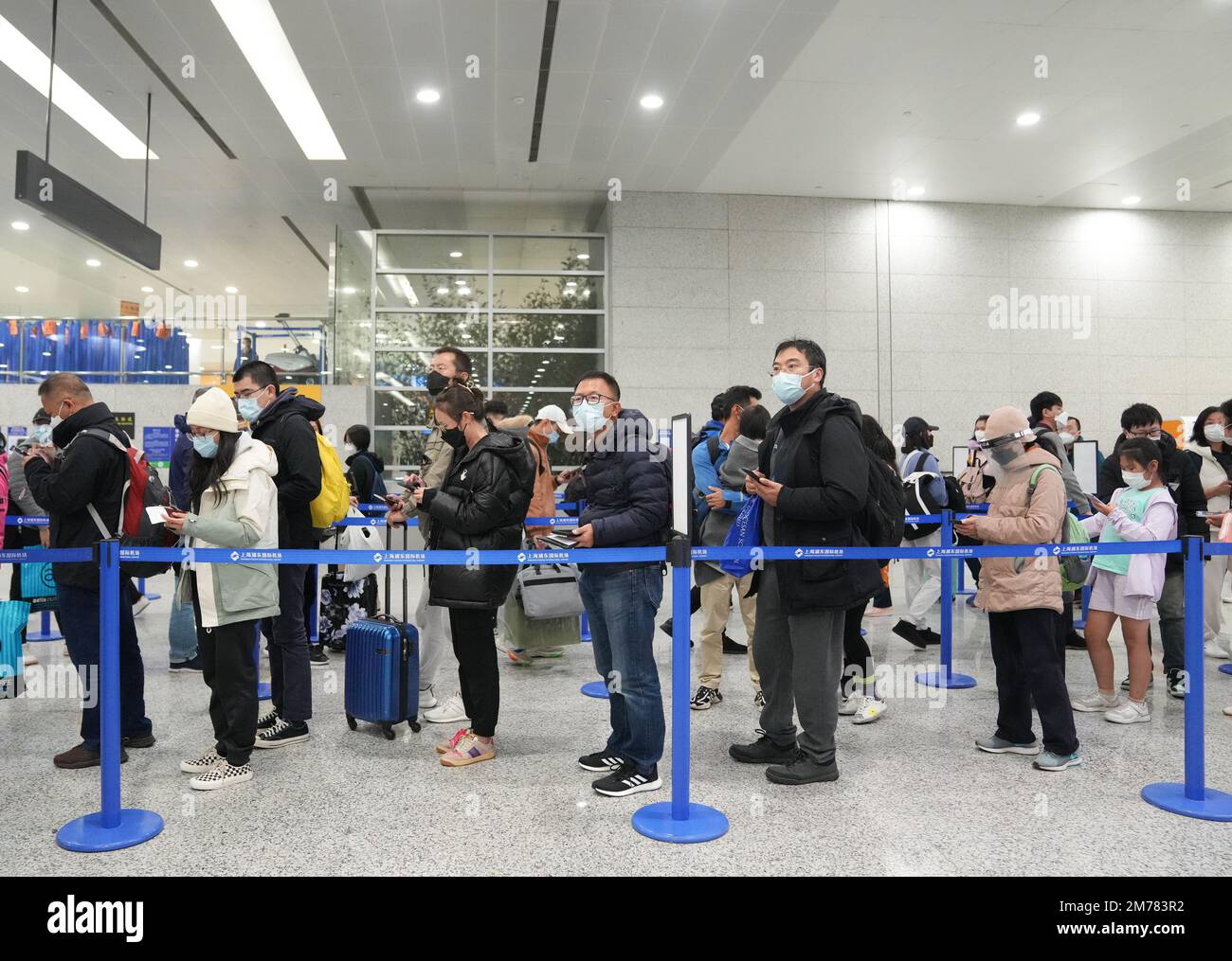 Shanghai. 8th Jan, 2023. Passengers queue up to go through entry ...