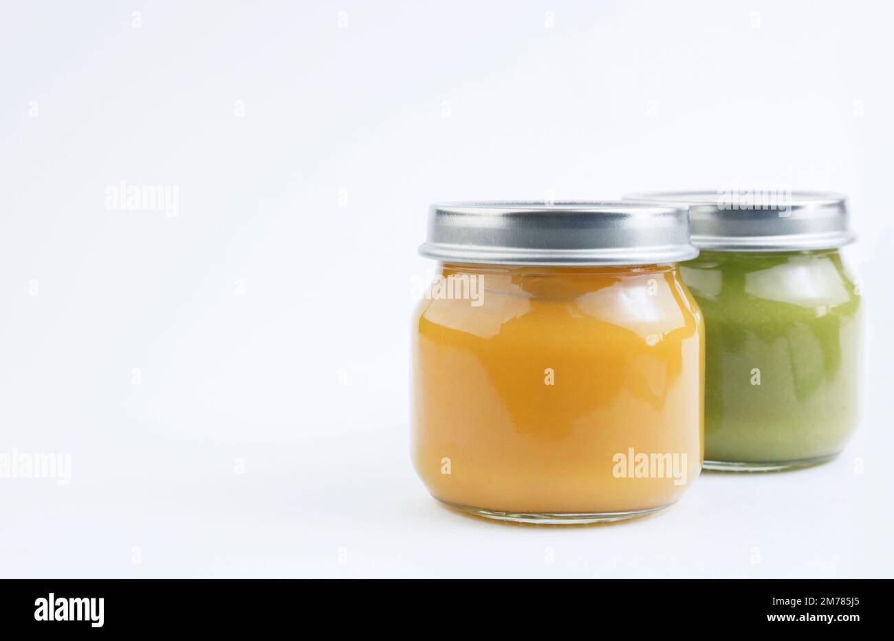 Baby vegetable or fruit puree in a glass jar on a white background ...