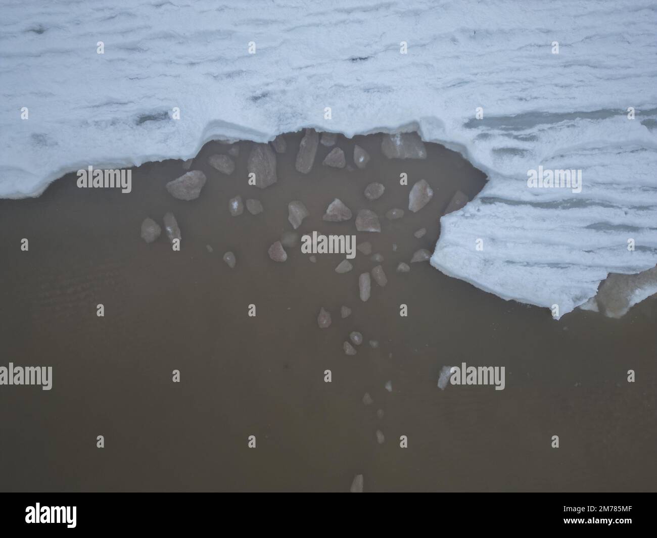 Aerial top down view of broken off ice pieces washing against frozen ...