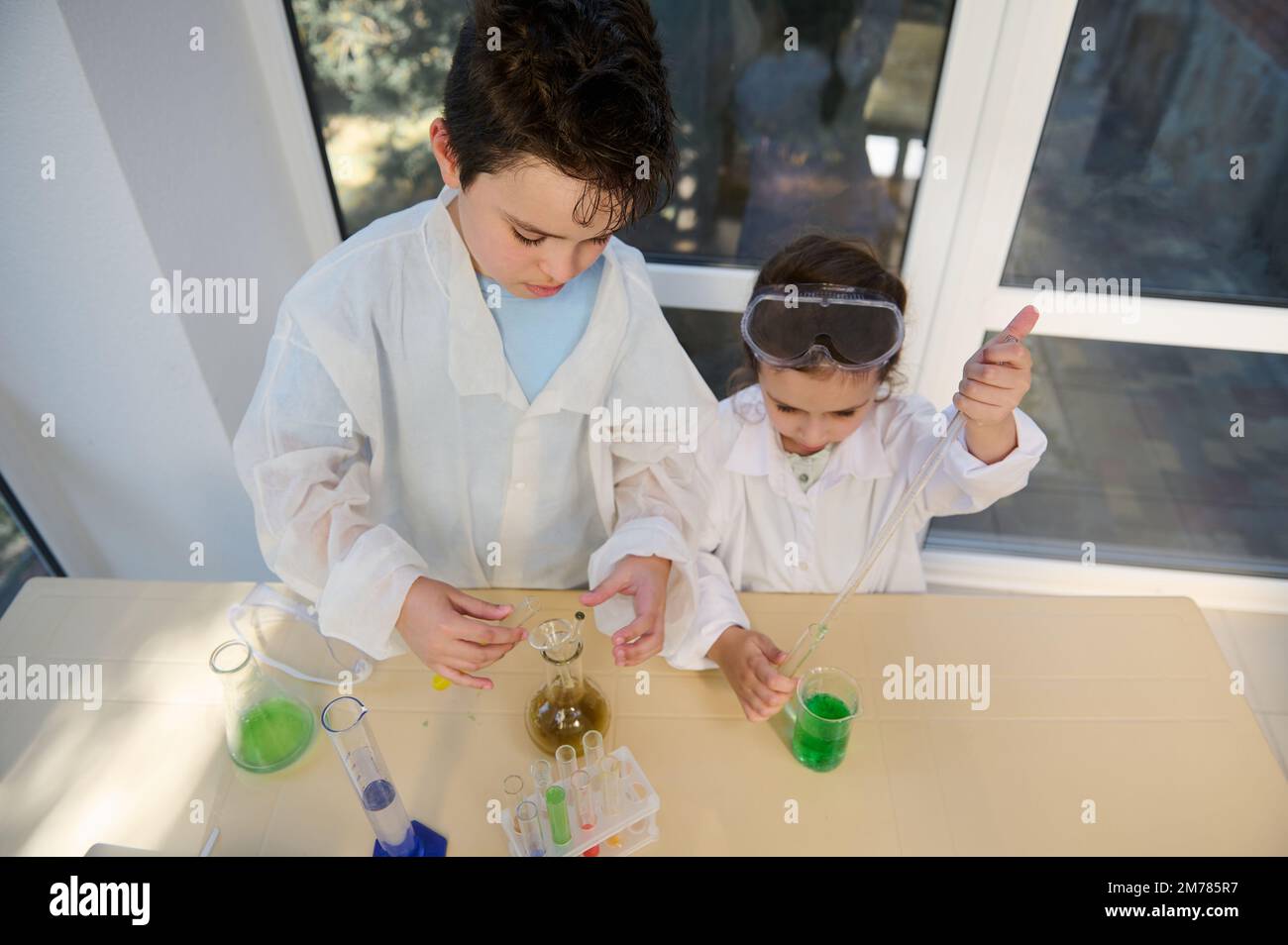 Top view two smart kids - chemist scientists doing experiments in ...