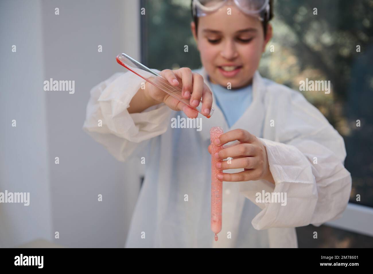 Close-up schoolboy's hands hold test tubes with solution coming out ...