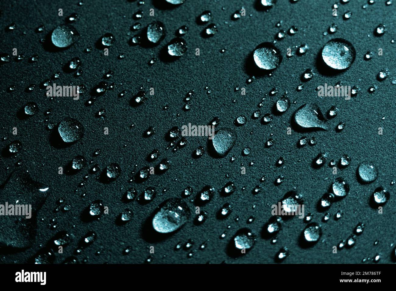 Round drops of water on dark background. Through transparent drops of ...