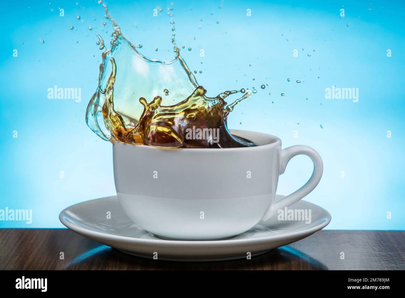 Cup of coffee splashing on blue background Stock Photo - Alamy