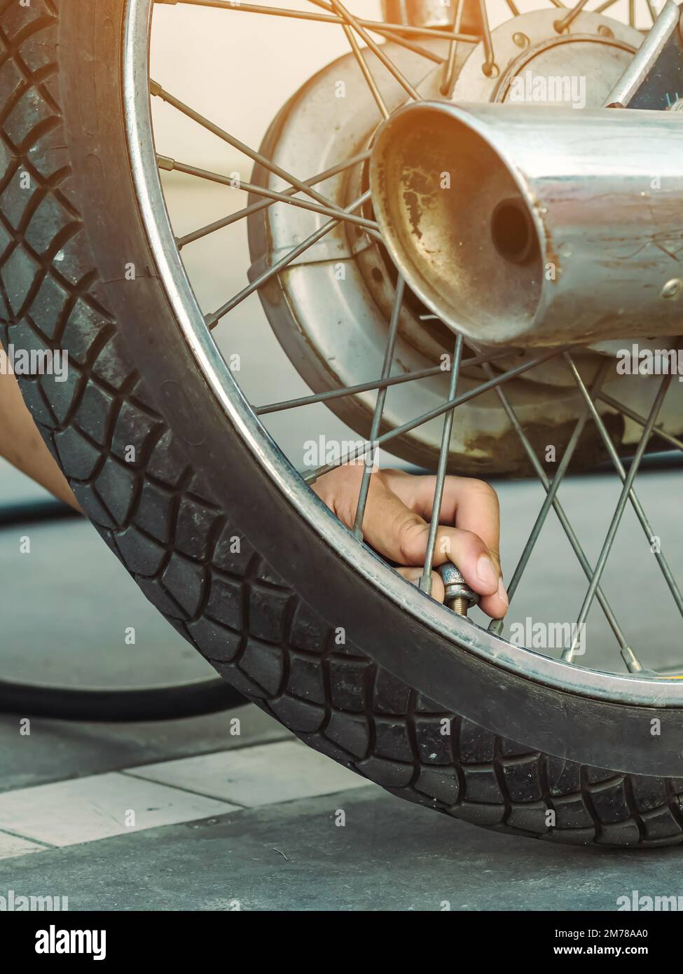 Hands of man check inflator pressure and inflates a tire on motorcycle ...
