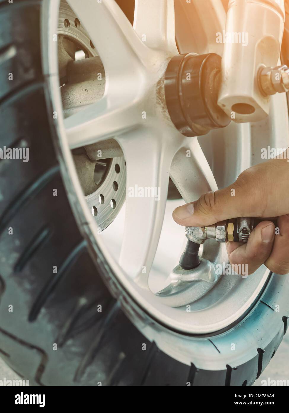 Hands of man check inflator pressure and inflates a tire on motorcycle ...