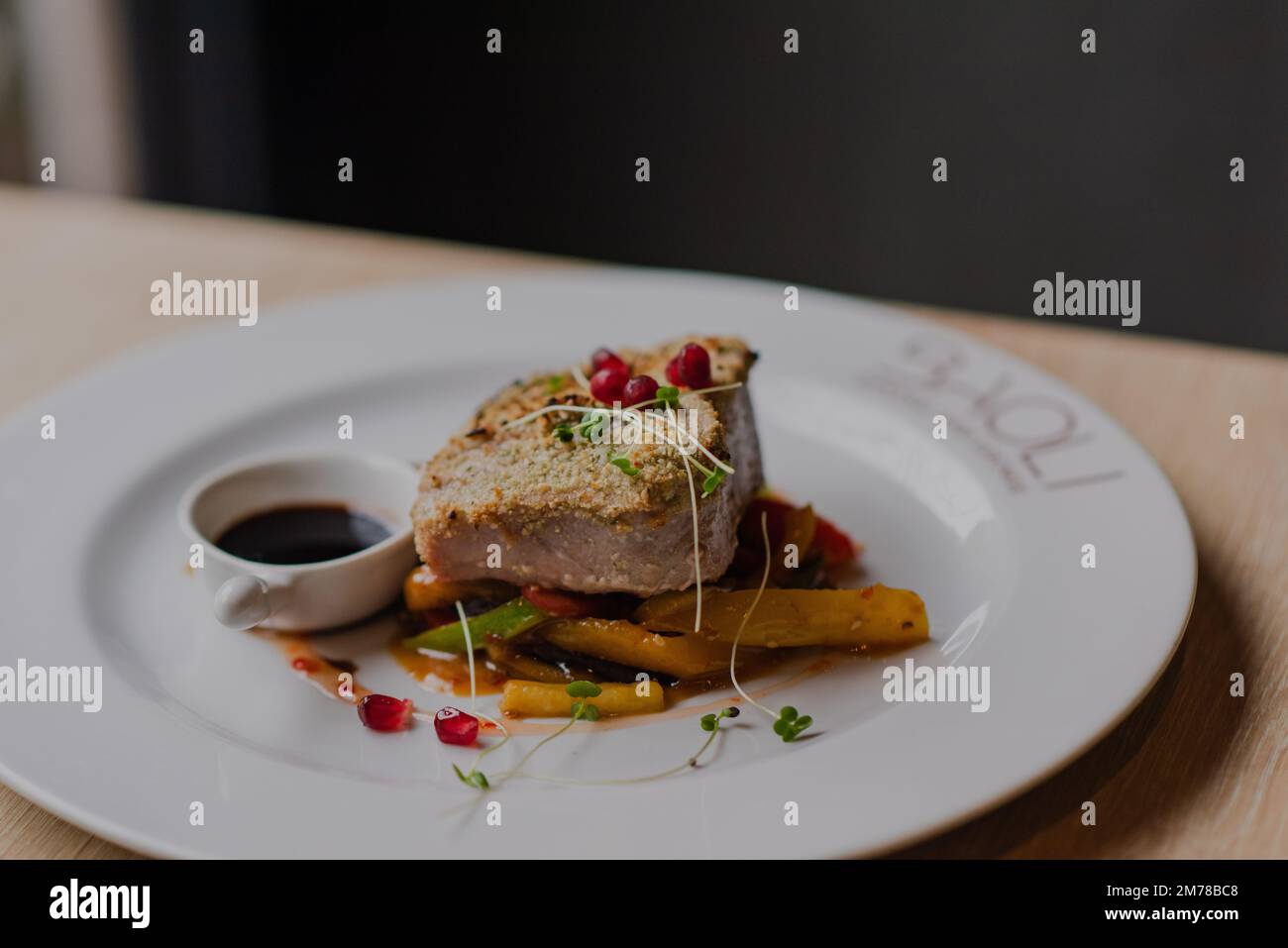 A closeup of a dish with sauce on a white table a cup of coffee blurred ...