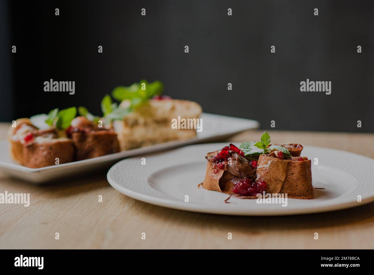Two deserts on white plates on a wooden table against dark, blurred ...