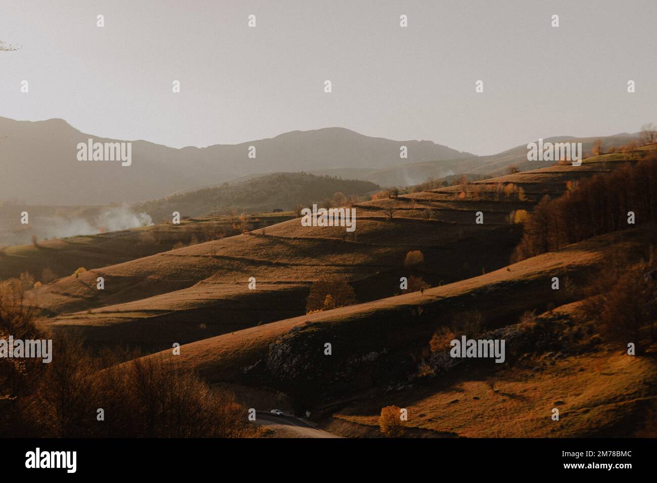 A high-angle of an autumn landscape with sunlit yellow valleys, misty ...