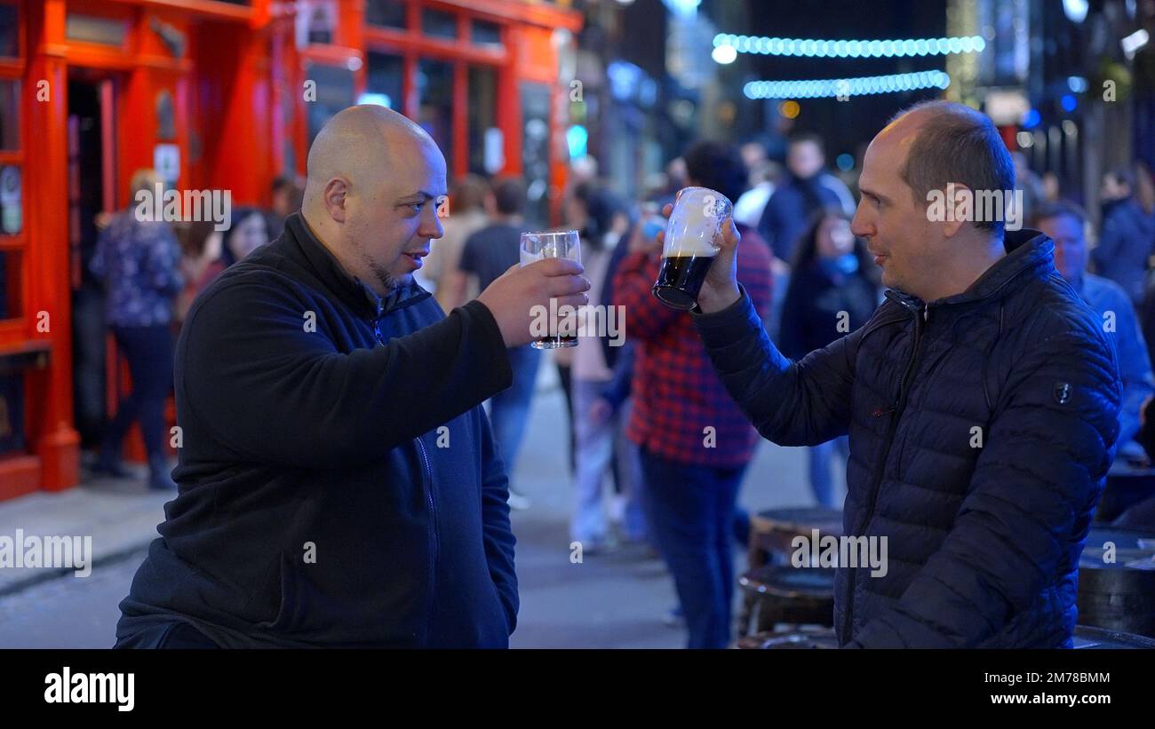 Guys drinking a beer in the Temple Bar district of Dublin by night ...