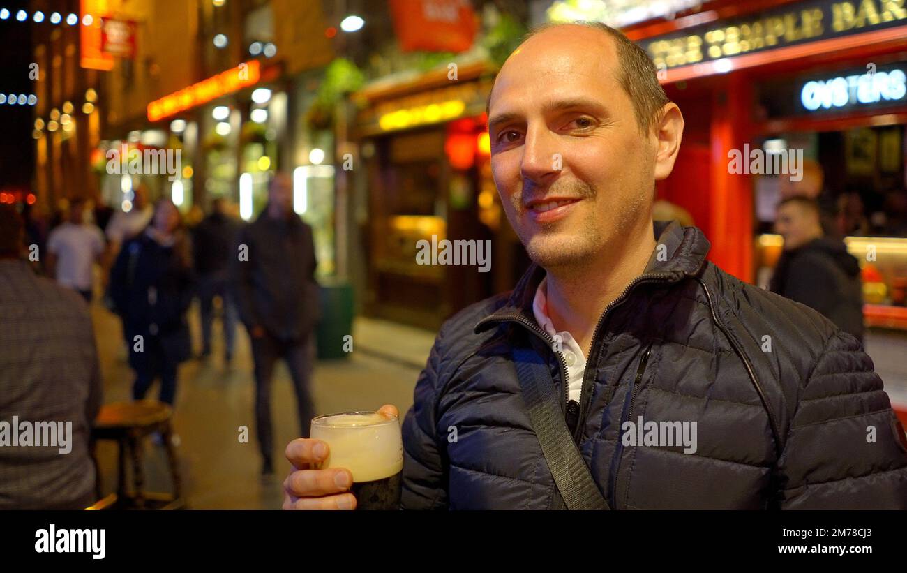Guys drinking a beer in the Temple Bar district of Dublin by night ...