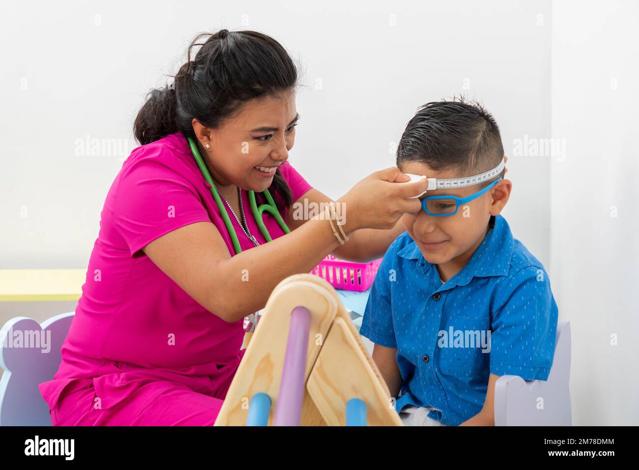 Latina pediatrician doctor, taking measurement of a child's head in her ...