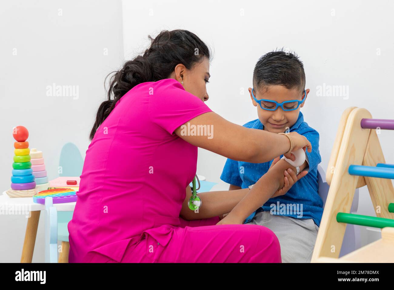 Latina pediatrician doctor, taking measurement of a child's arm in her ...