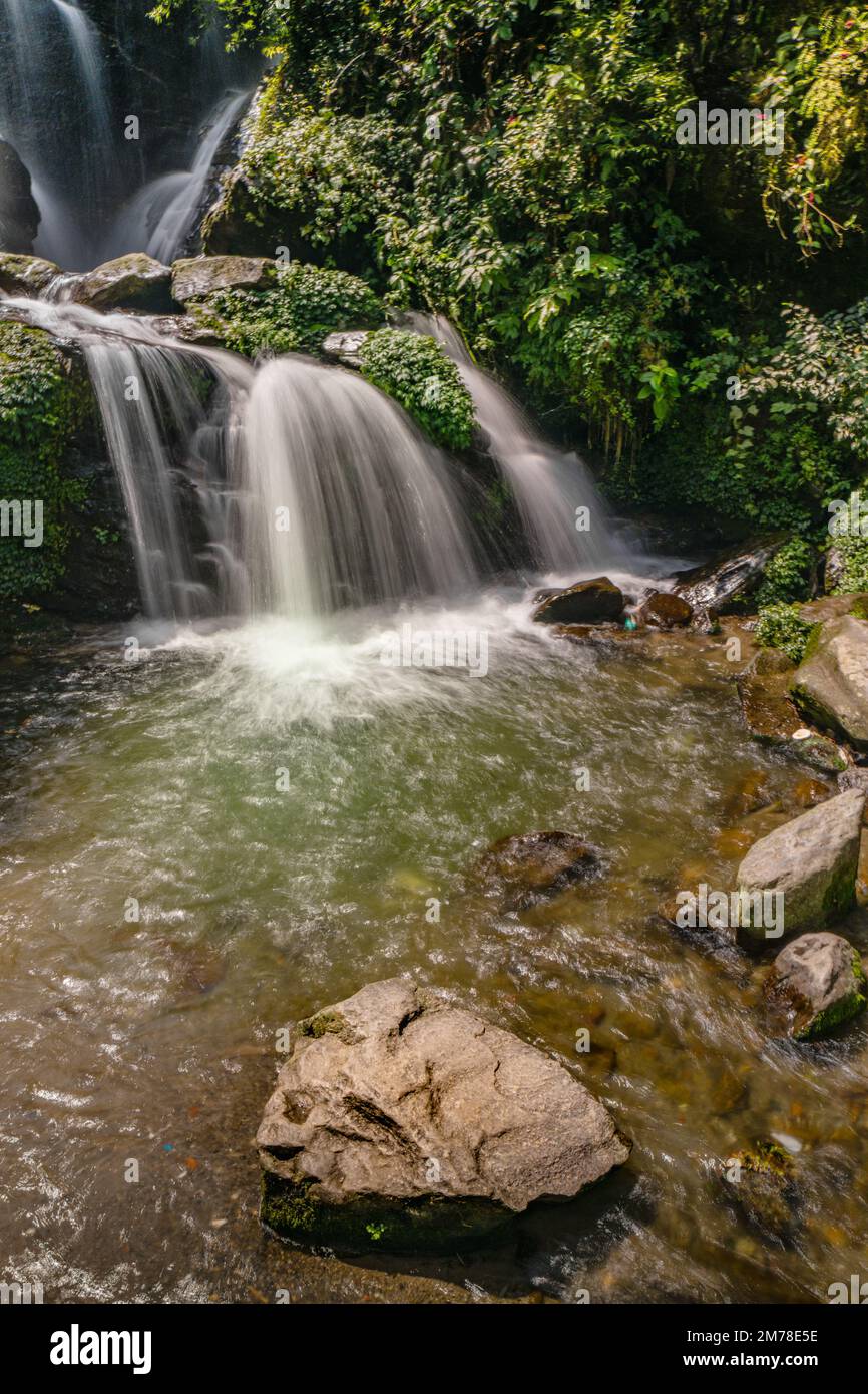 A vertical shot of the waterfall cascading over rocks in sunlight in ...