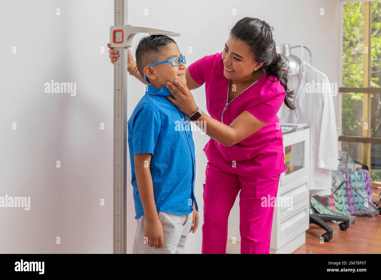 Pediatric female doctor holding a child's head while measuring it with ...