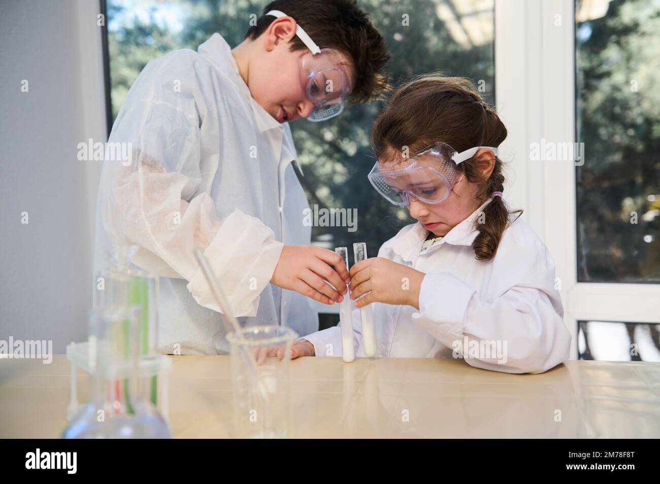 Concentrated smart kids conduct chemical experiment, watch the reaction ...