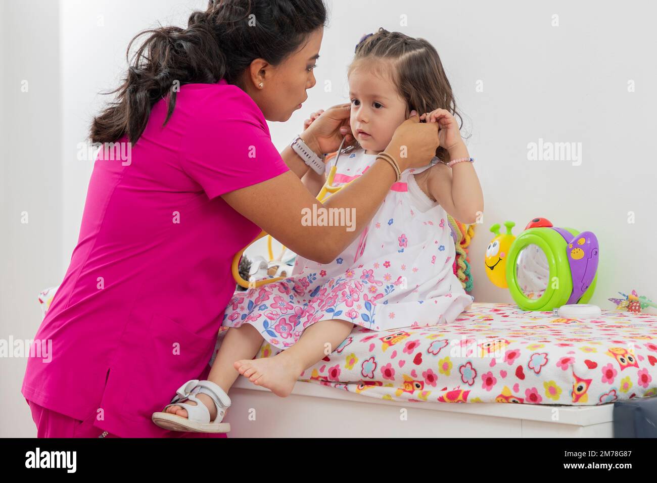 Nurse putting a stethoscope to a girl, so that she can play with it ...