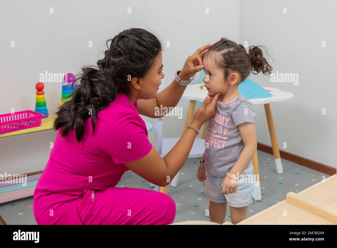 Pediatrician rewards a girl who is in his office, placing a star of ...
