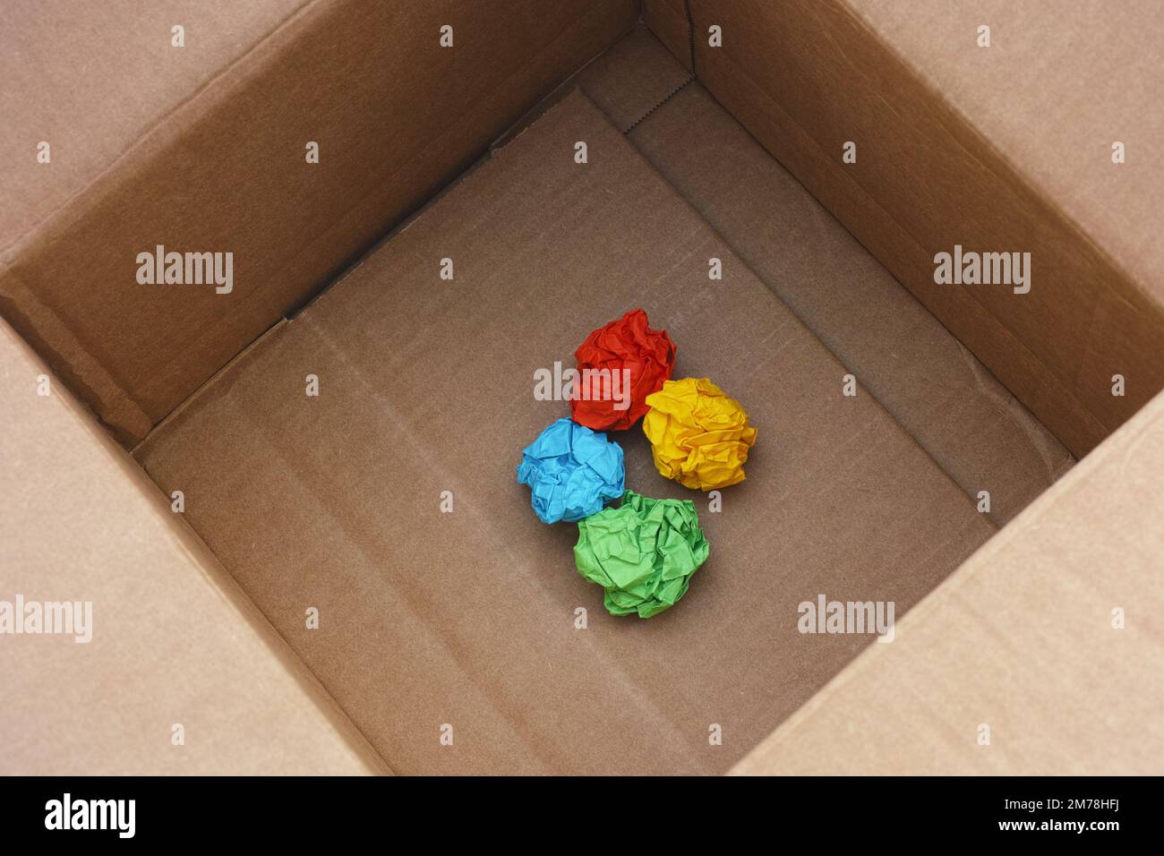 A cardboard box with crumpled colorful paper balls inside. Idea concept ...