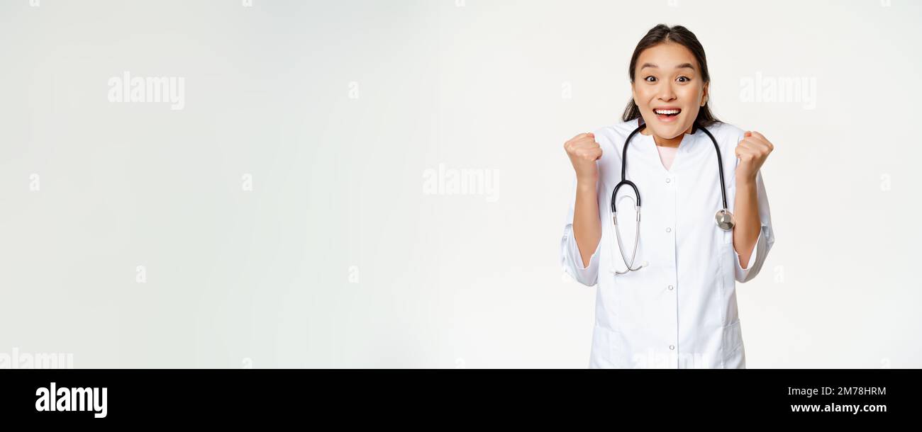 Enthusiastic female asian doctor celebrating, looking hopeful and happy ...