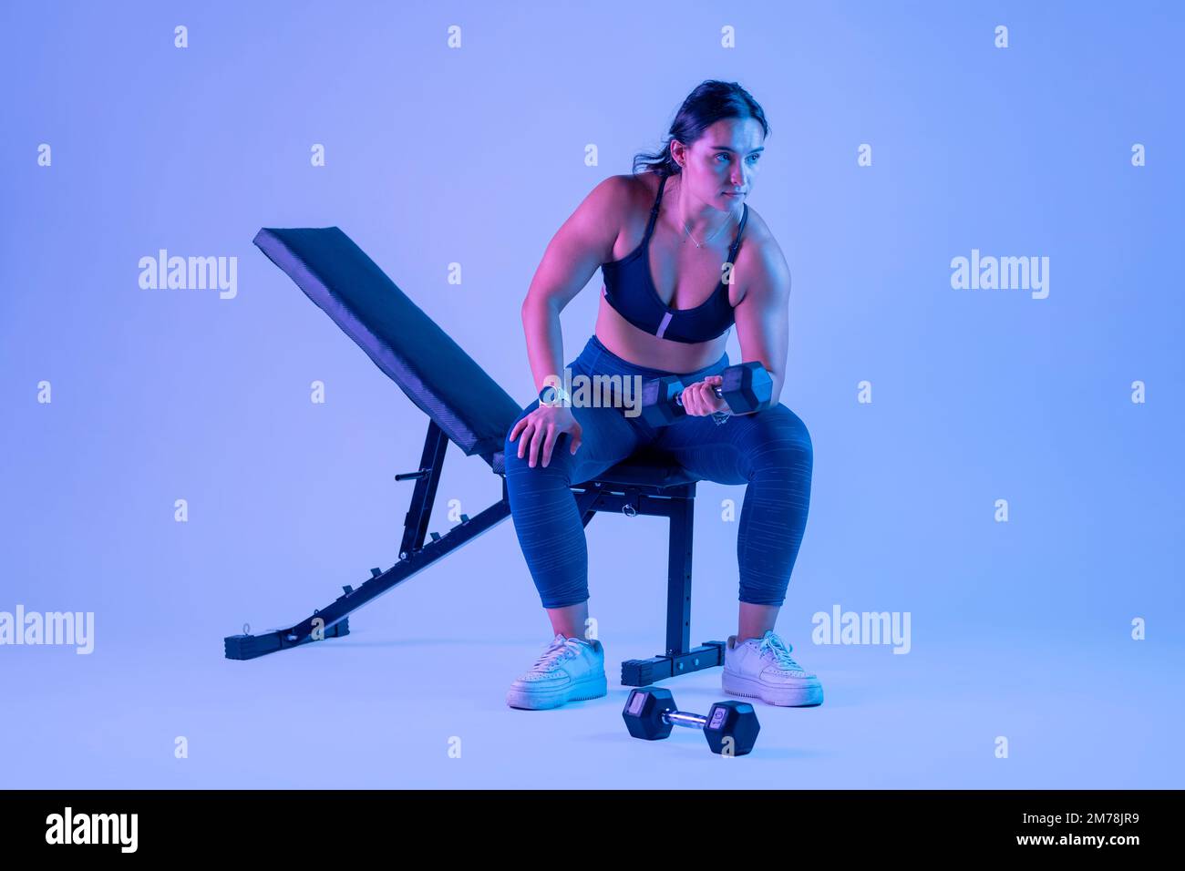 woman in sportswear doing biceps exercises, sitting on a bench Stock ...