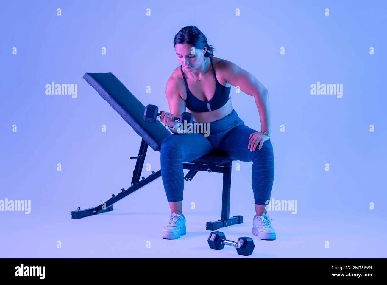 woman in sportswear doing biceps exercises, sitting on a bench Stock ...
