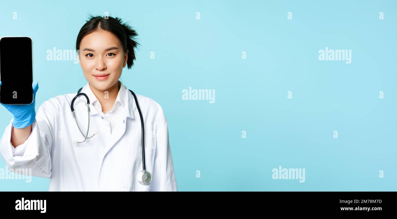 Web medical doctor concept. Smiling asian physician showing mobile ...