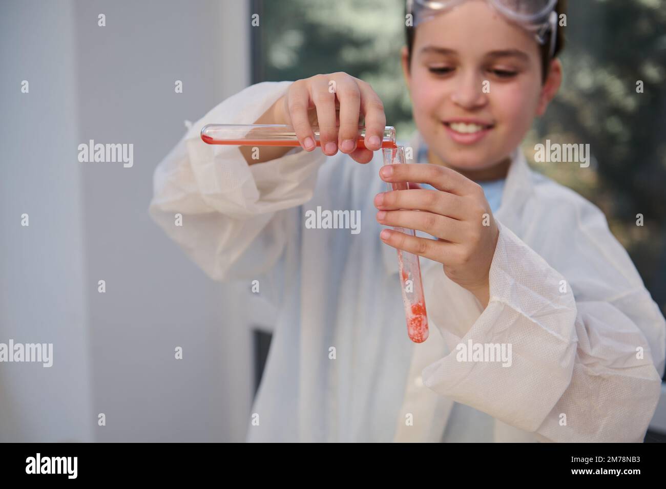 Details: hands of blurred schoolboy pouring reagent into a test tube ...