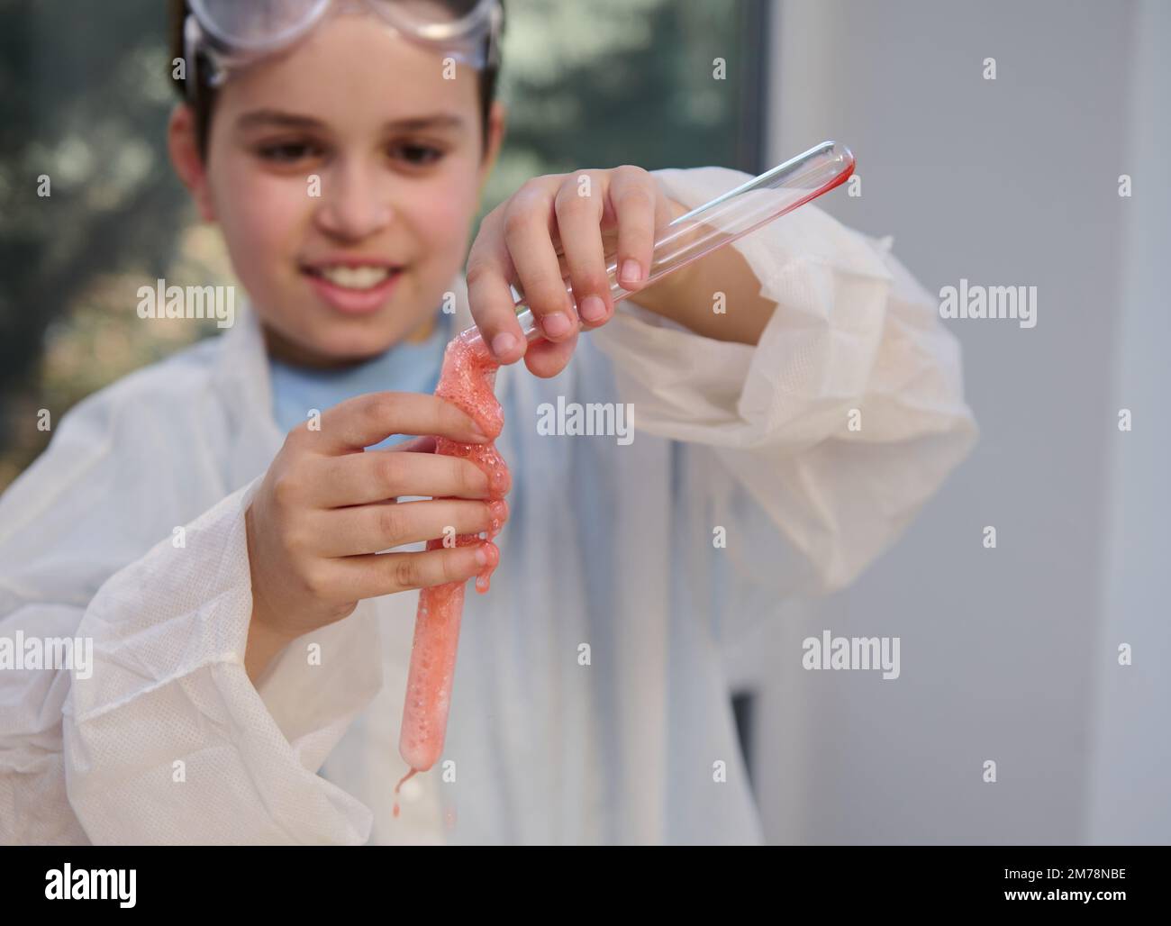 Focus on schoolboy's hands, holding test tubes with ongoing chemical ...