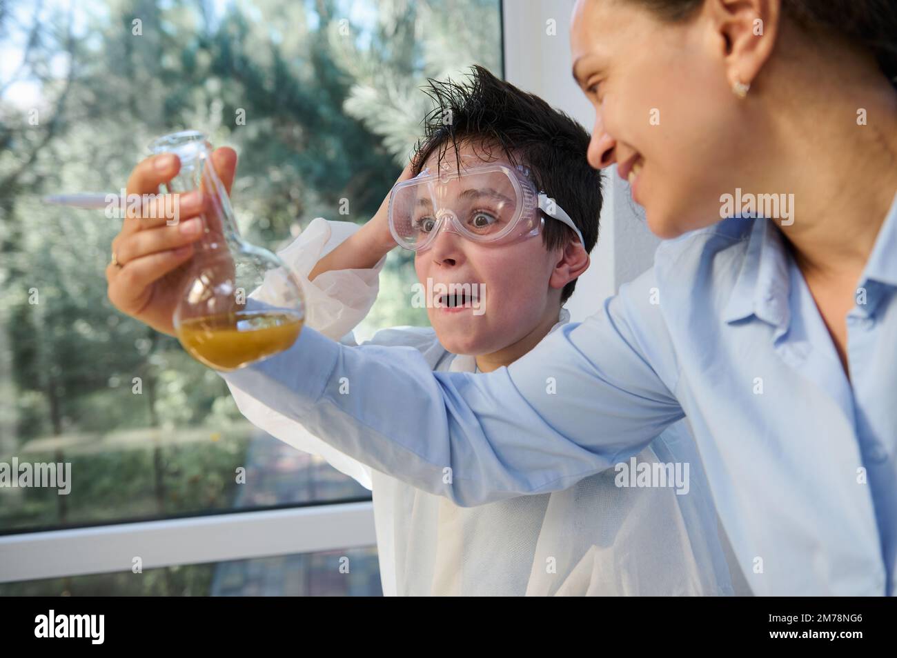 Amazed smart schoolboy expressing surprise while watching the chemical ...