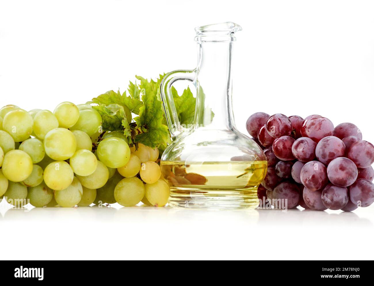 Grape seed oil on white background. The image also shows light grapes ...