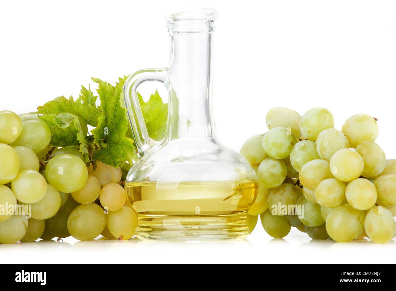 Grape seed oil on white background. The image also shows light grapes ...