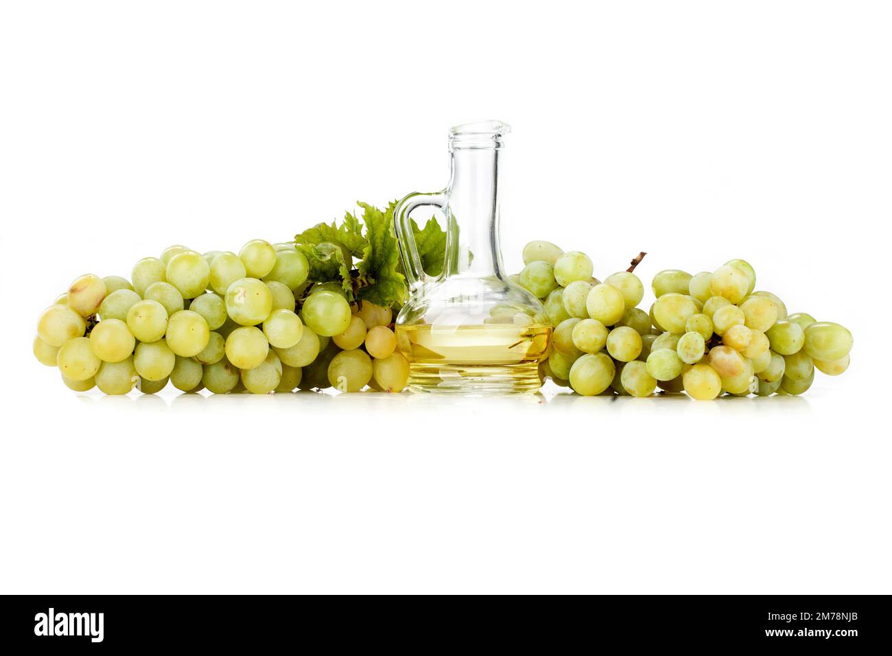 Grape seed oil on white background. The image also shows light grapes ...