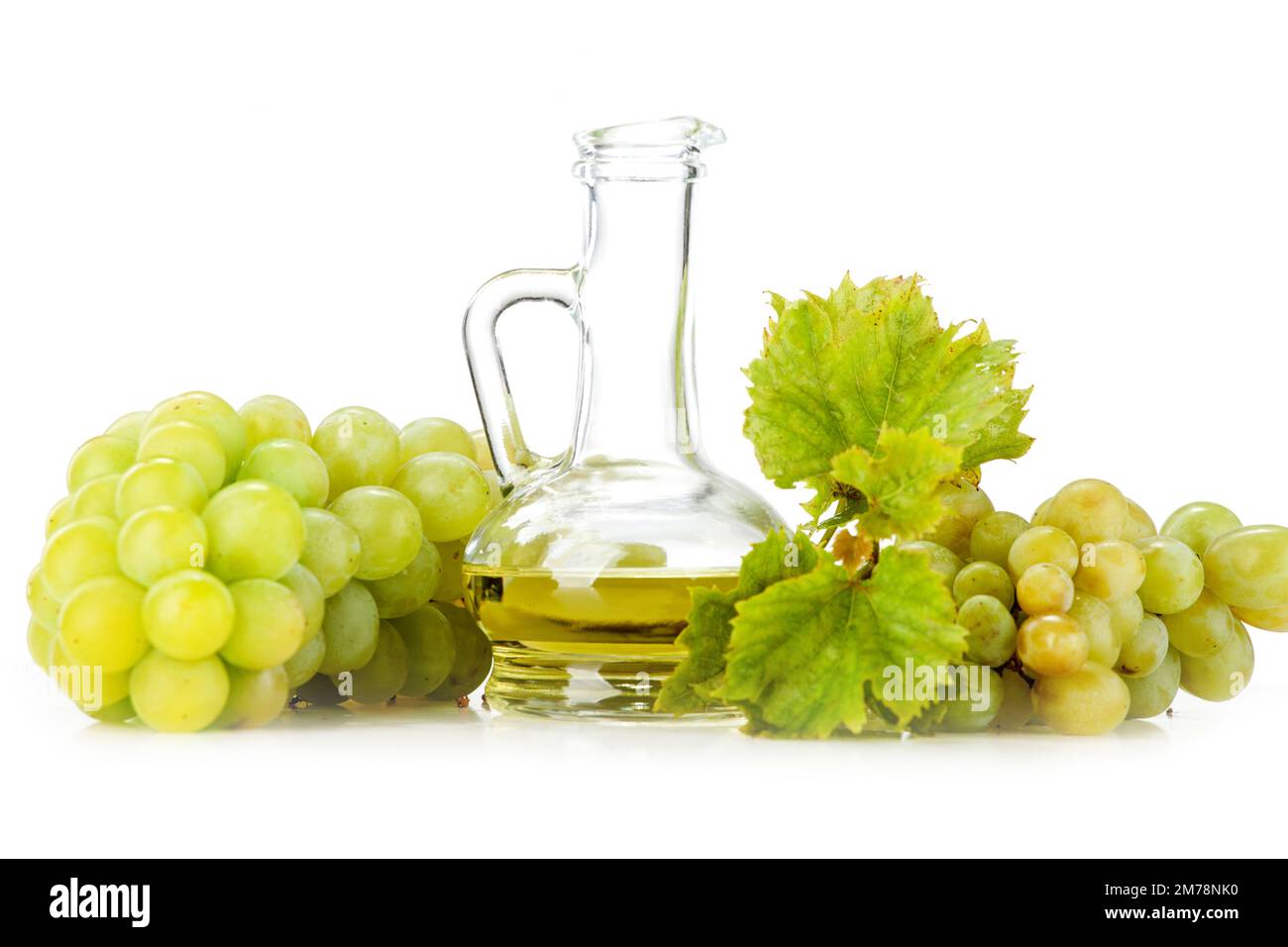 Grape seed oil on white background. The image also shows light grapes ...