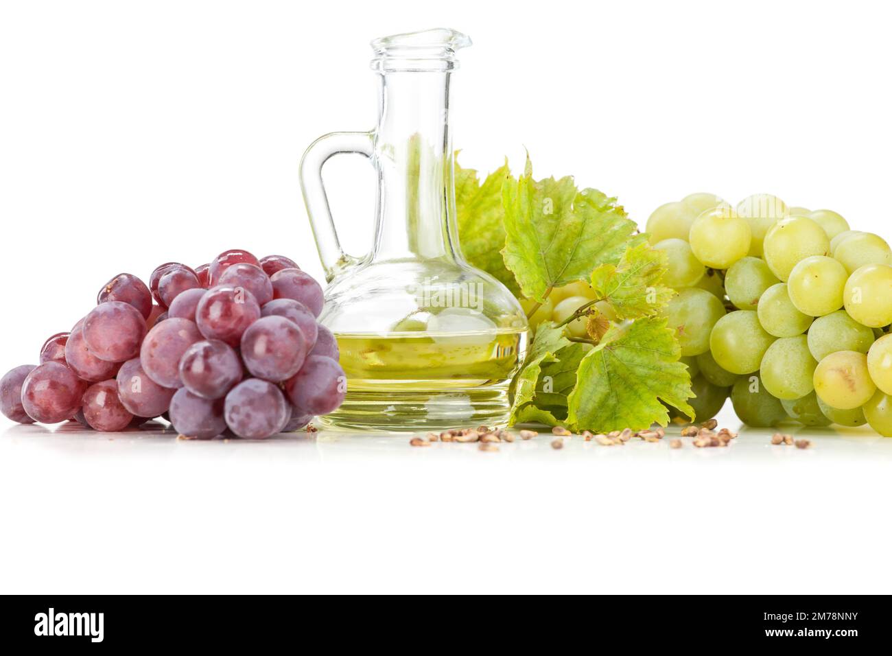 Grape seed oil on white background. The image also shows light grapes ...