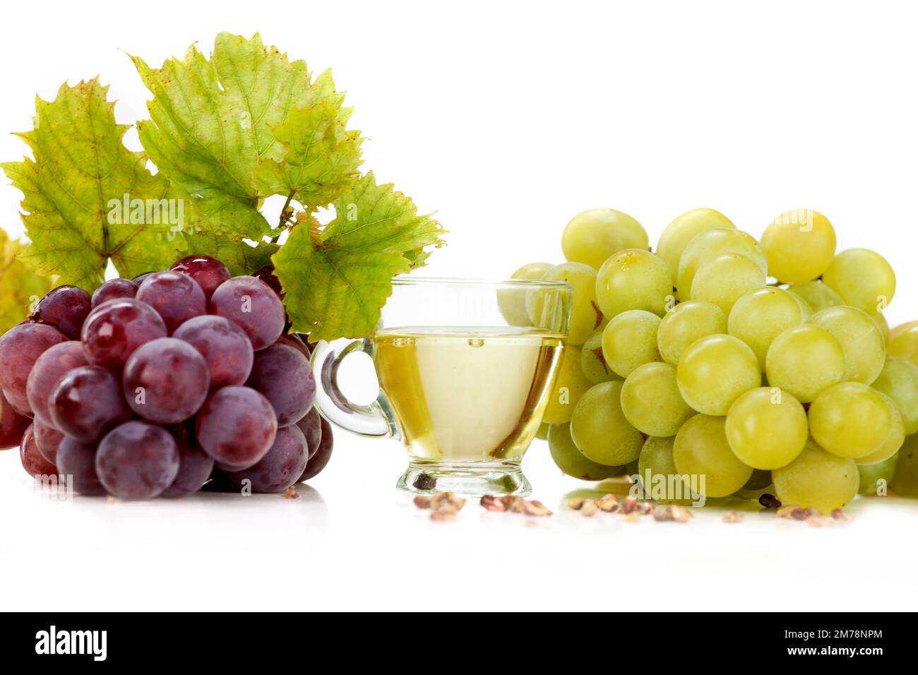 Grape seed oil on white background. The image also shows light grapes ...