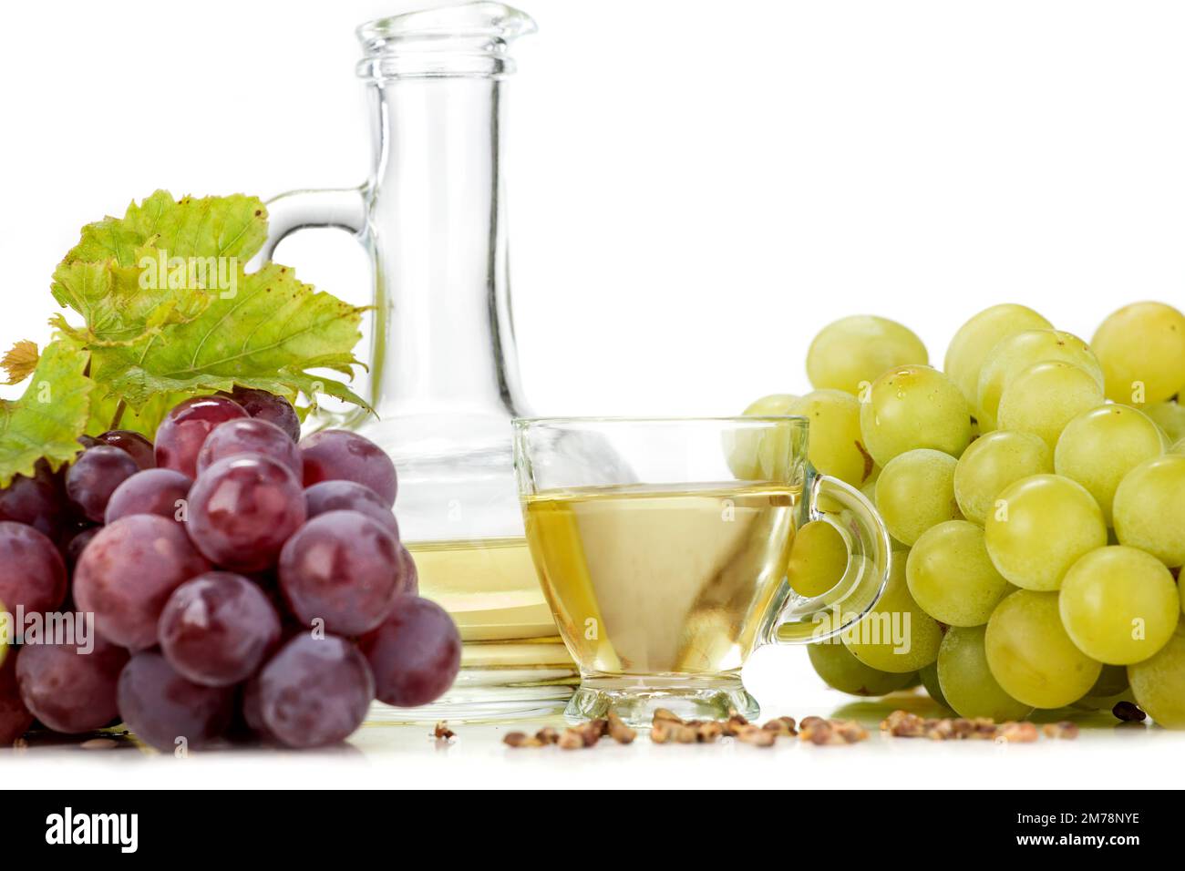 Grape seed oil on white background. The image also shows light grapes ...