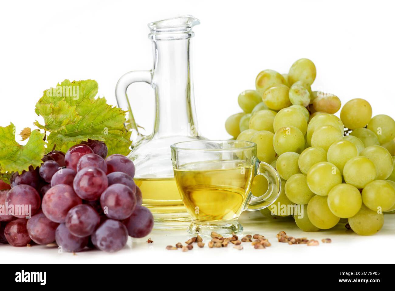 Grape seed oil on white background. The image also shows light grapes ...