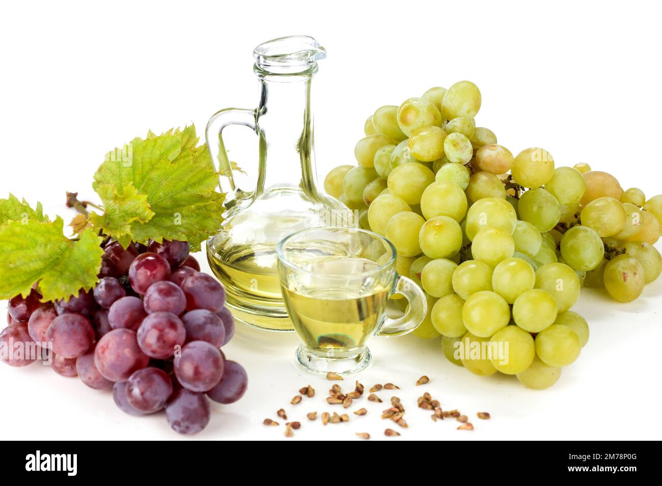 Grape seed oil on white background. The image also shows light grapes ...