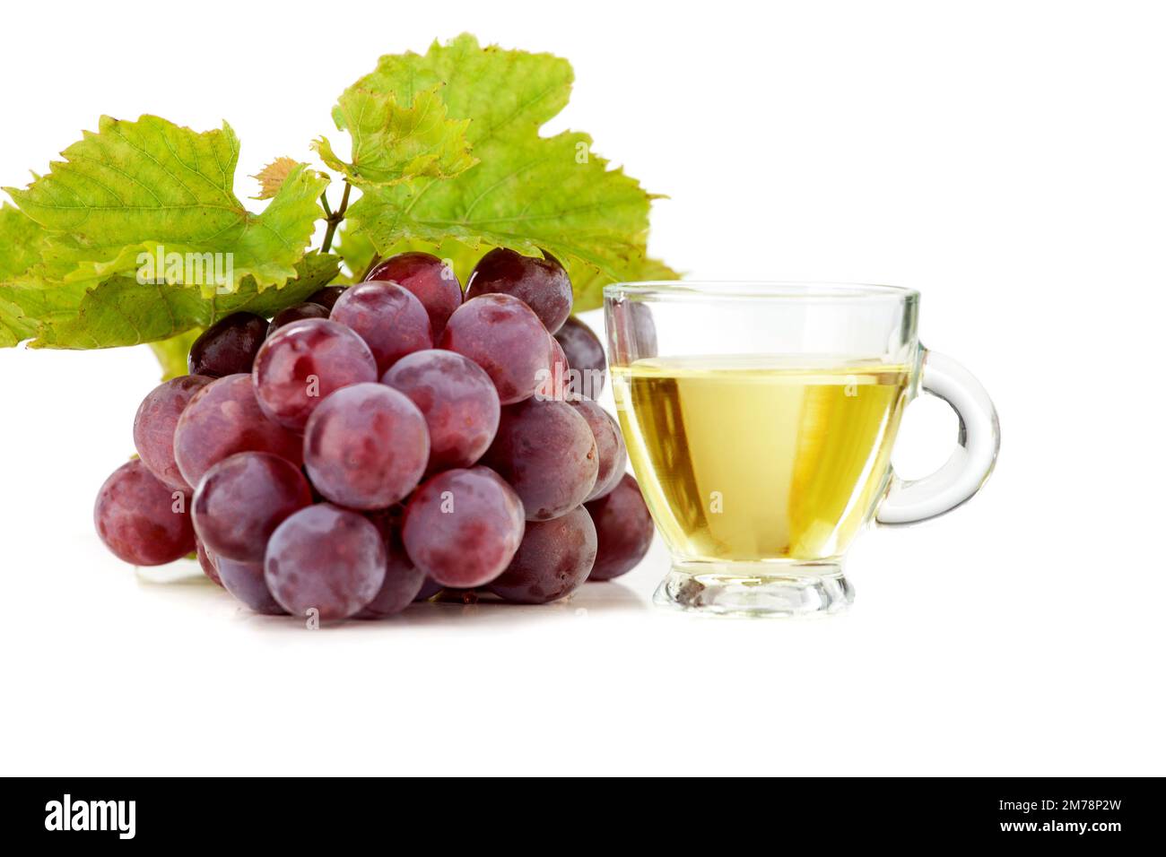 Grape seed oil on white background. The image also shows light grapes ...