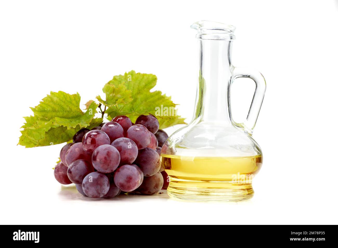 Grape seed oil on white background. The image also shows light grapes ...