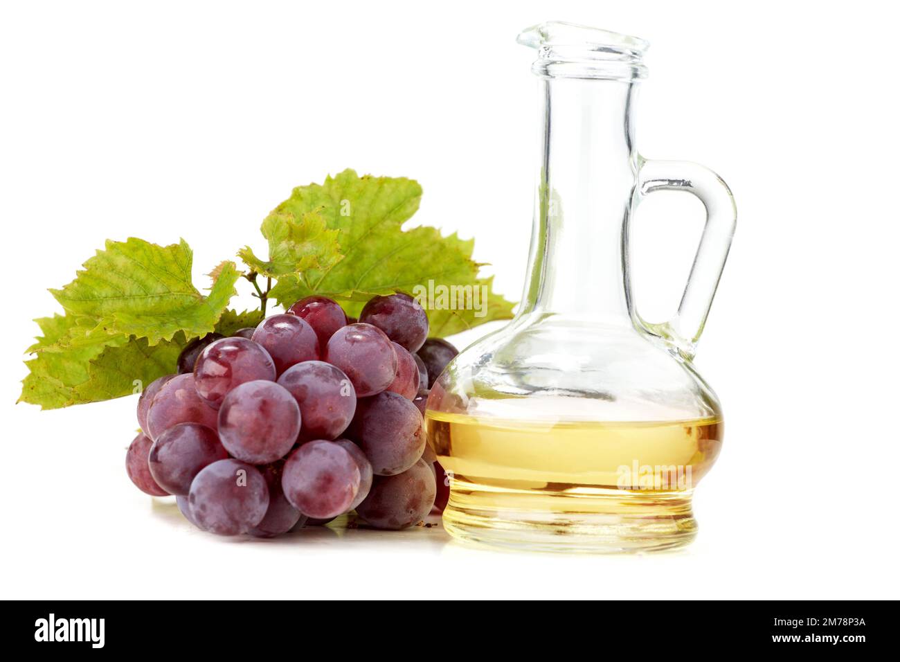 Grape seed oil on white background. The image also shows light grapes ...