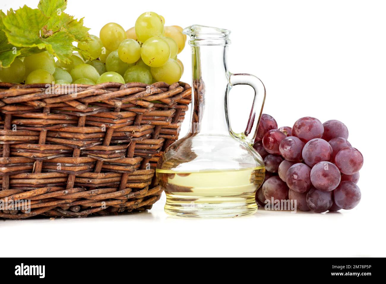 Grape seed oil on white background. The image also shows light grapes ...